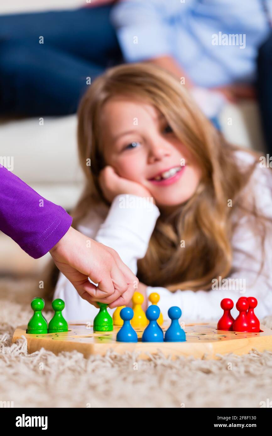 Family playing board game ludo at home on the floor, focus on the arm ...