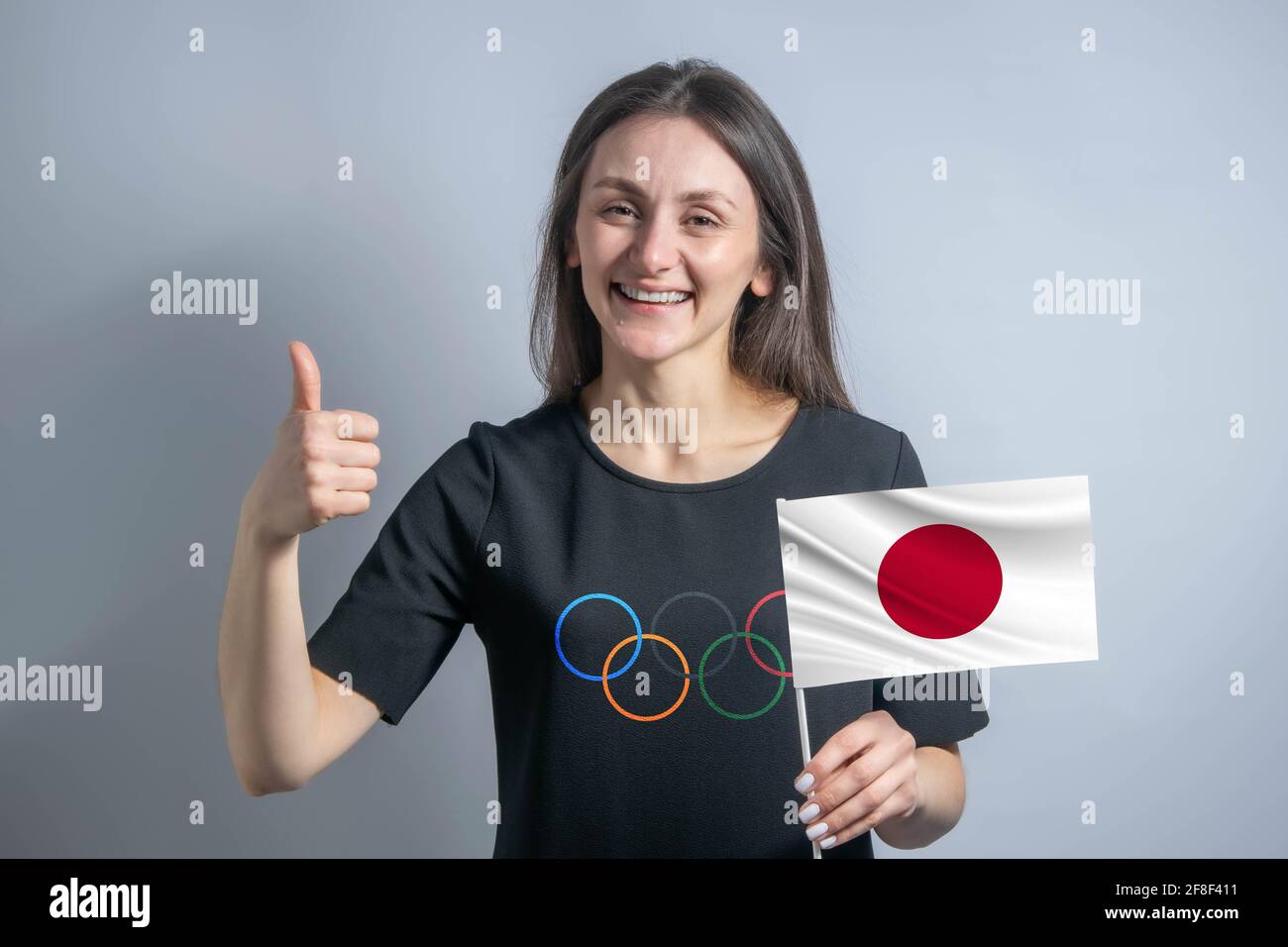 Happy young white woman holding flag of Japan and shows the class ...