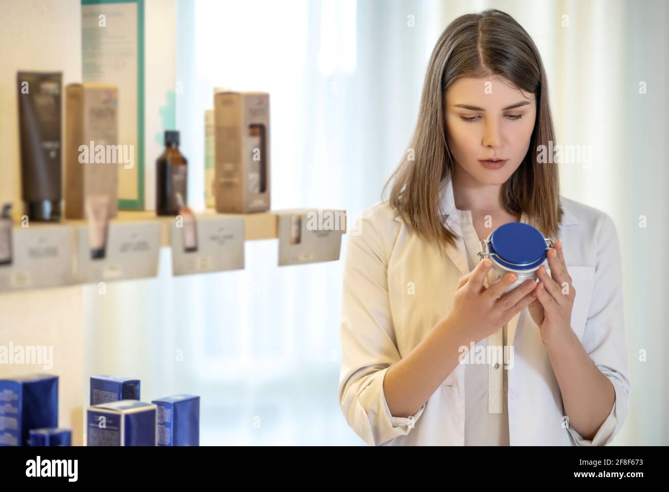 Pretty shop assistant examining new products and looking involved Stock ...