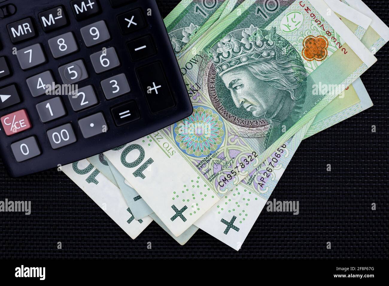 Calculator and Polish banknotes of PLN 100 on a black background. Photo ...