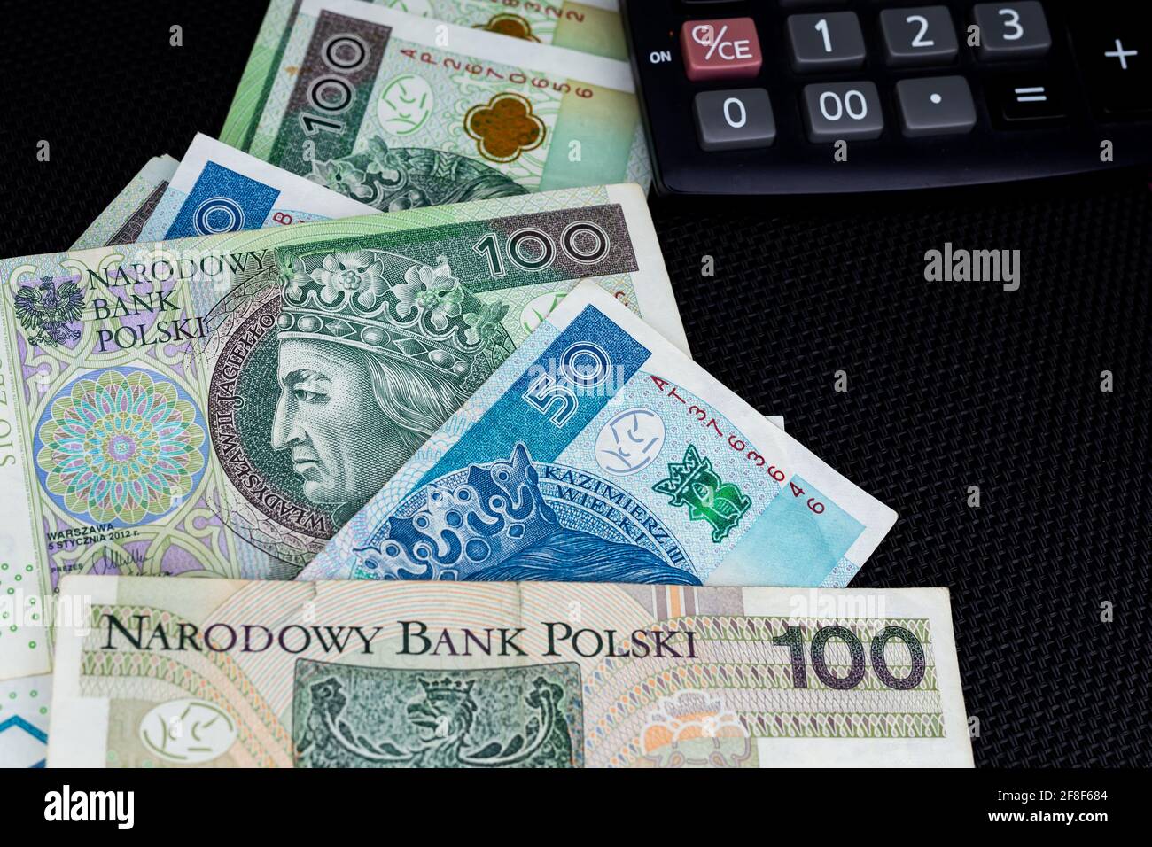 Calculator and Polish banknotes of PLN 100 and PLN 50 on a black ...