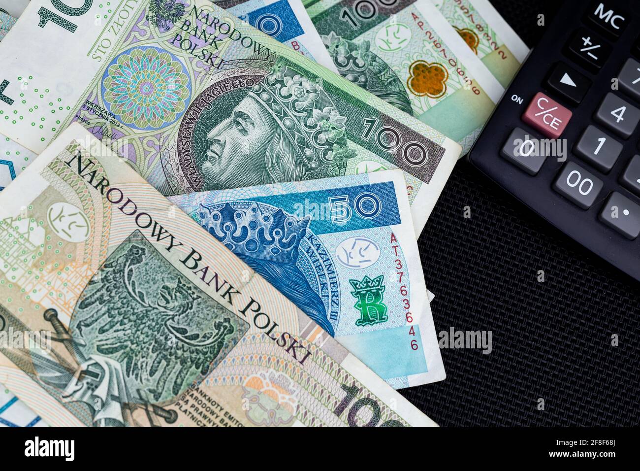 Calculator and Polish banknotes of PLN 100 and PLN 50 on a black ...