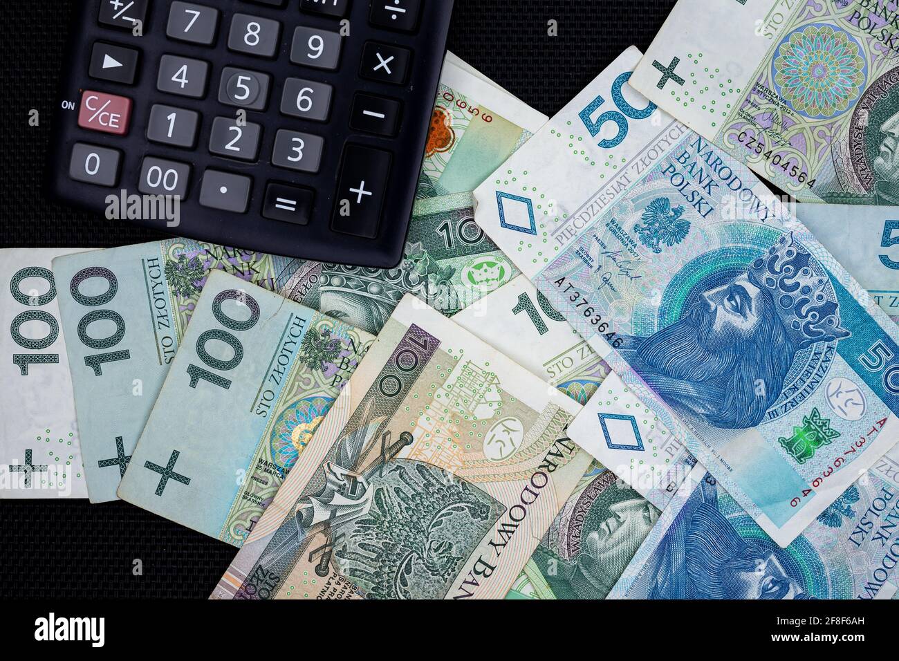 Calculator and Polish banknotes of PLN 100 and PLN 50 on a black ...