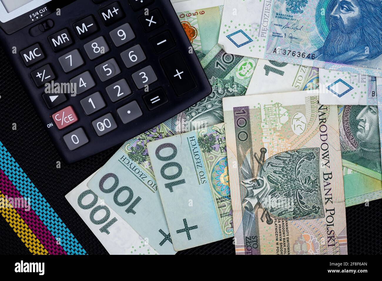 Calculator and Polish banknotes of PLN 100 and PLN 50 on a black ...