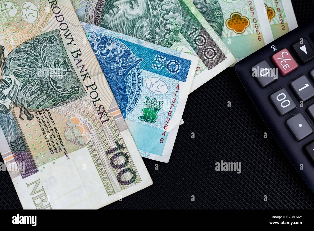 Calculator and Polish banknotes of PLN 100 and PLN 50 on a black ...