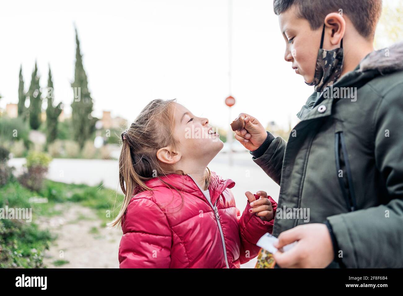 Portrait of two kids while eating and sharing a piece of chocolate ...