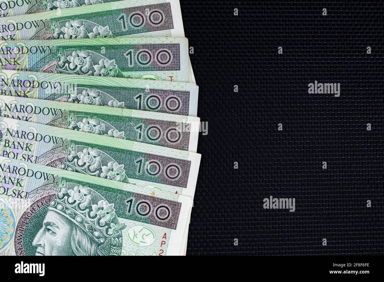Polish banknotes of PLN 100 on a black background. Photo taken under ...