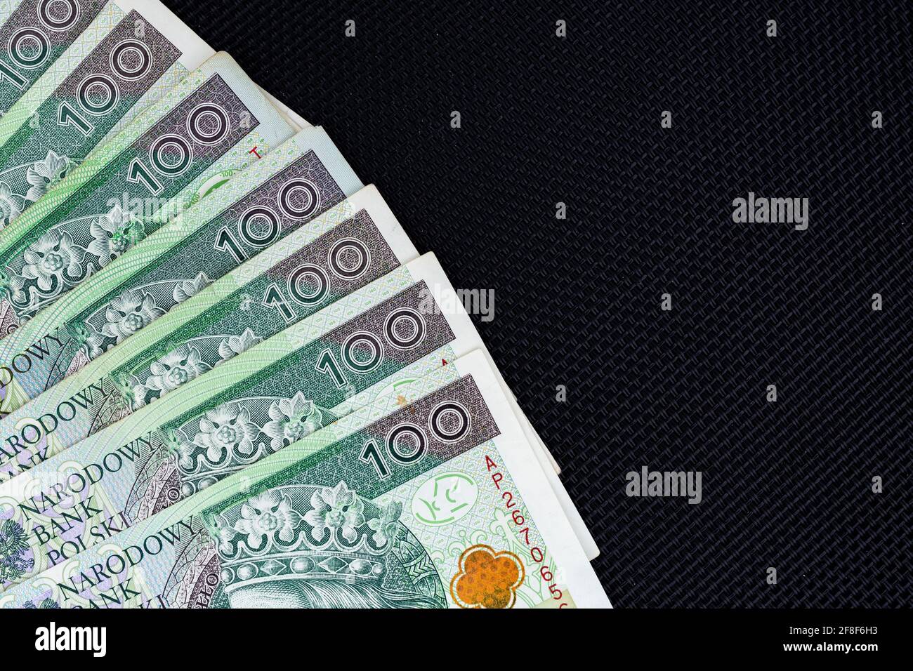 Polish banknotes of PLN 100 on a black background. Photo taken under ...
