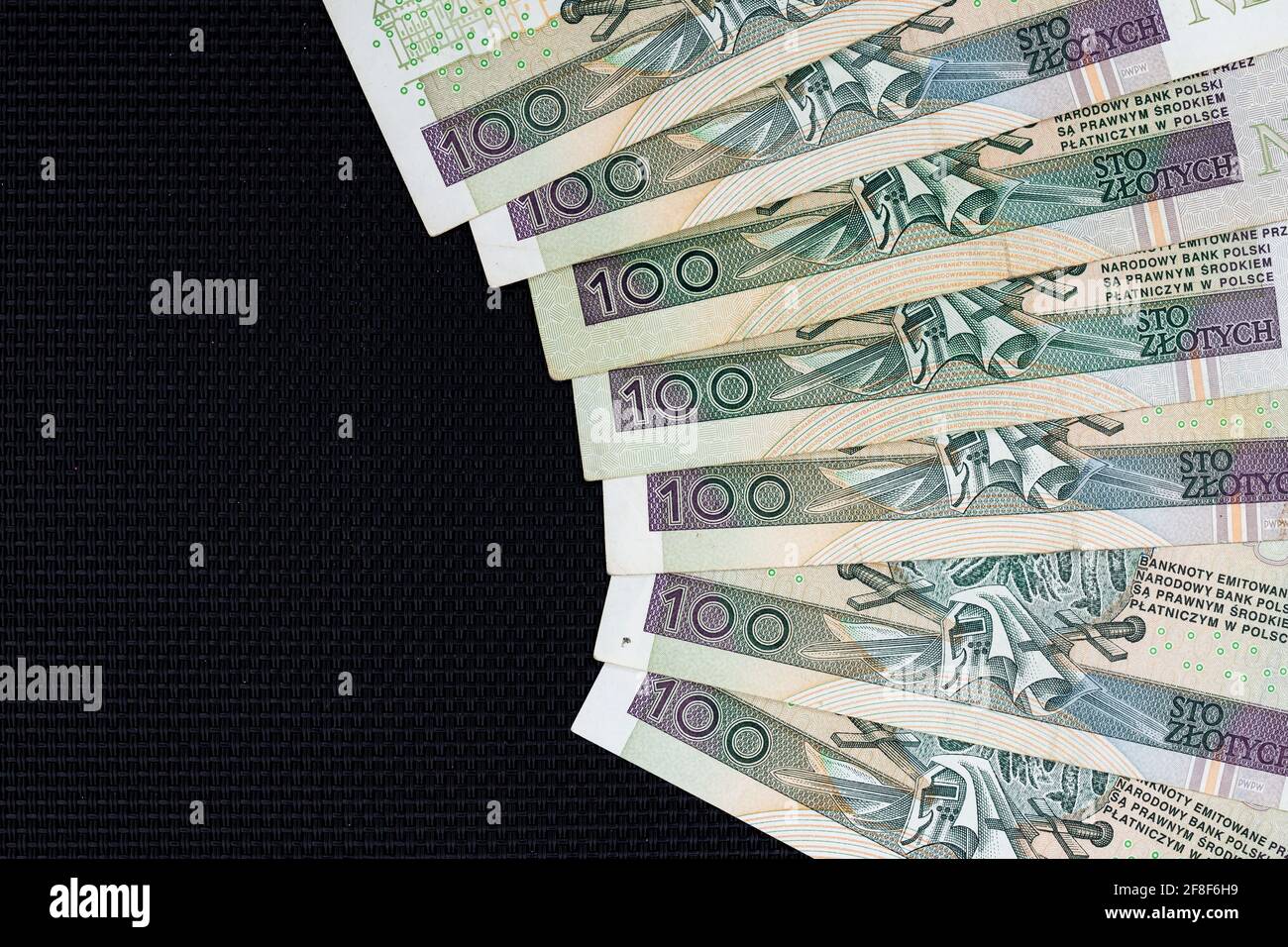 Polish banknotes of PLN 100 on a black background. Photo taken under ...