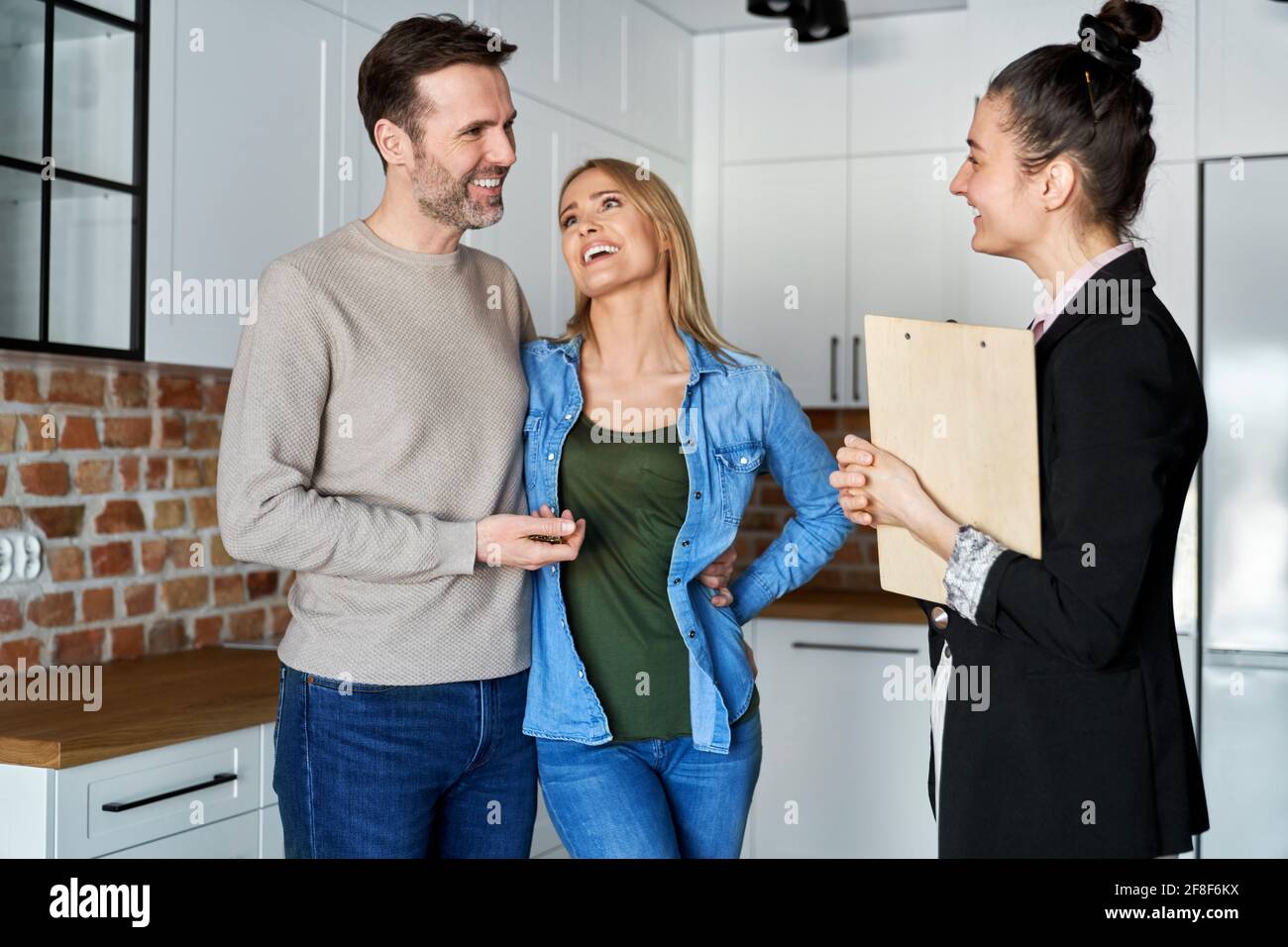 Happy couple talking to a real estate agent Stock Photo - Alamy