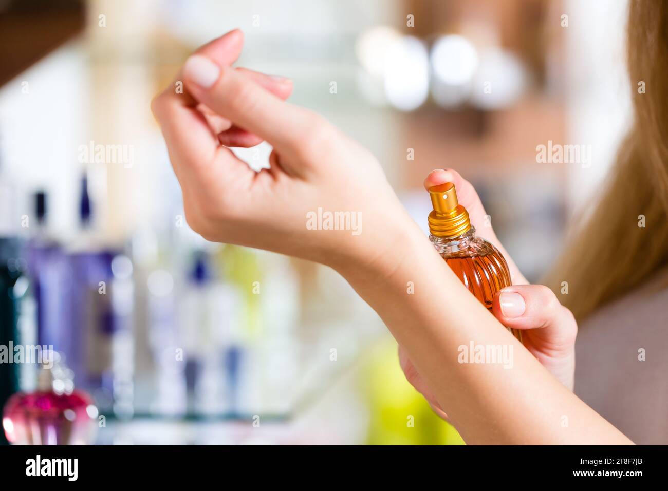 Young woman buying perfume in a shop or store, testing the fragrance on ...