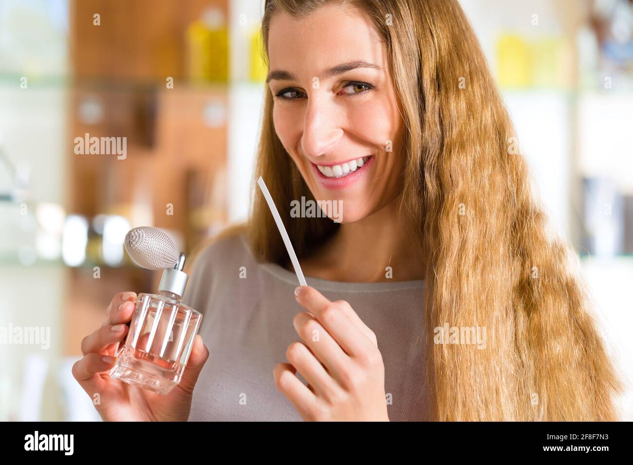 Young woman buying perfume in a shop or store, testing the fragrance ...
