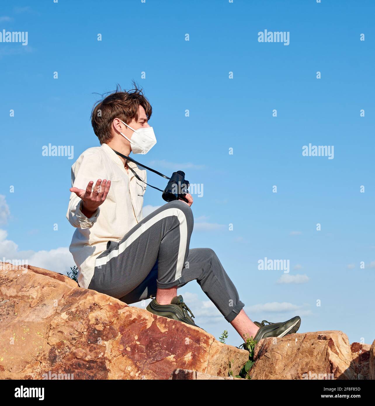Side view of an explorer from Spain in a mask sitting on a rock ...