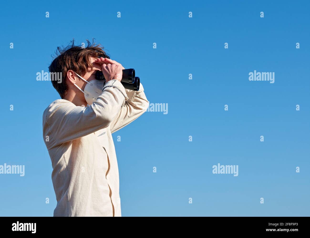 Spanish adventurous male traveler wearing a mask using binoculars and ...