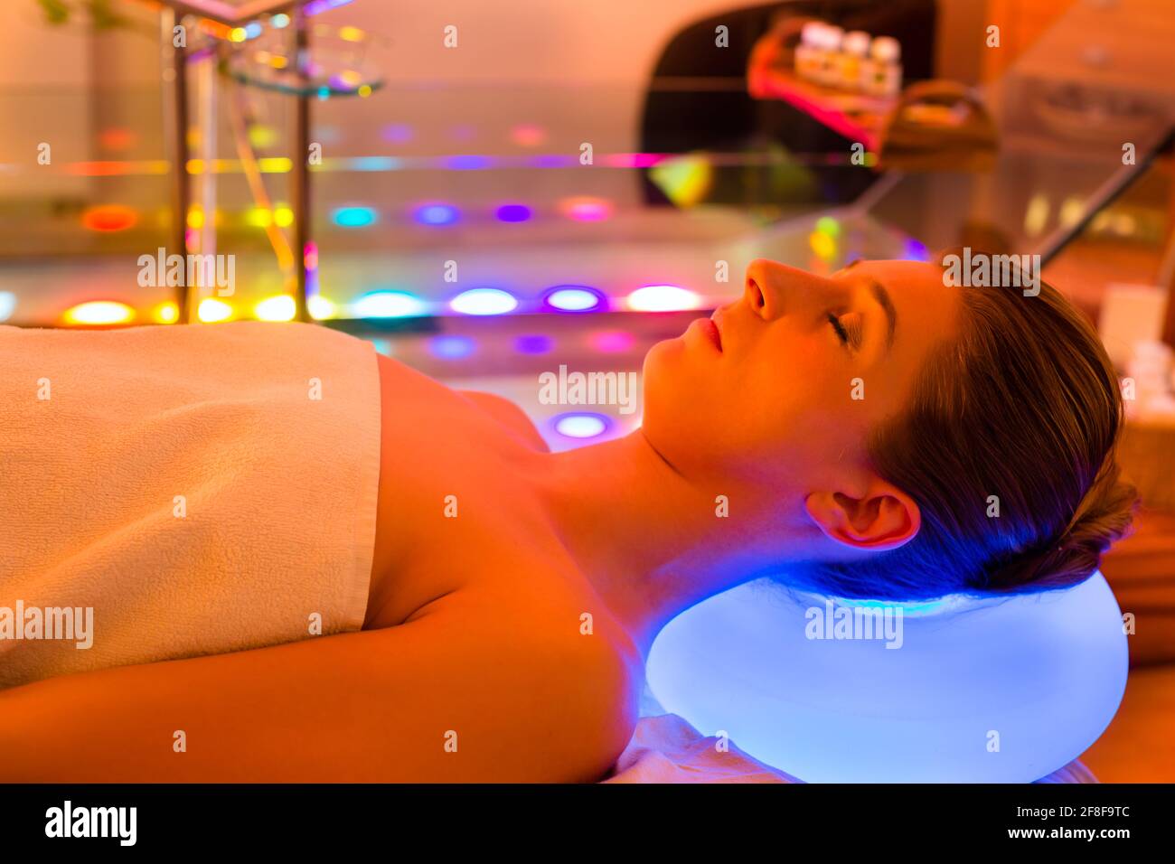 Woman enjoying therapy in spa with color therapy, colorful lights ...