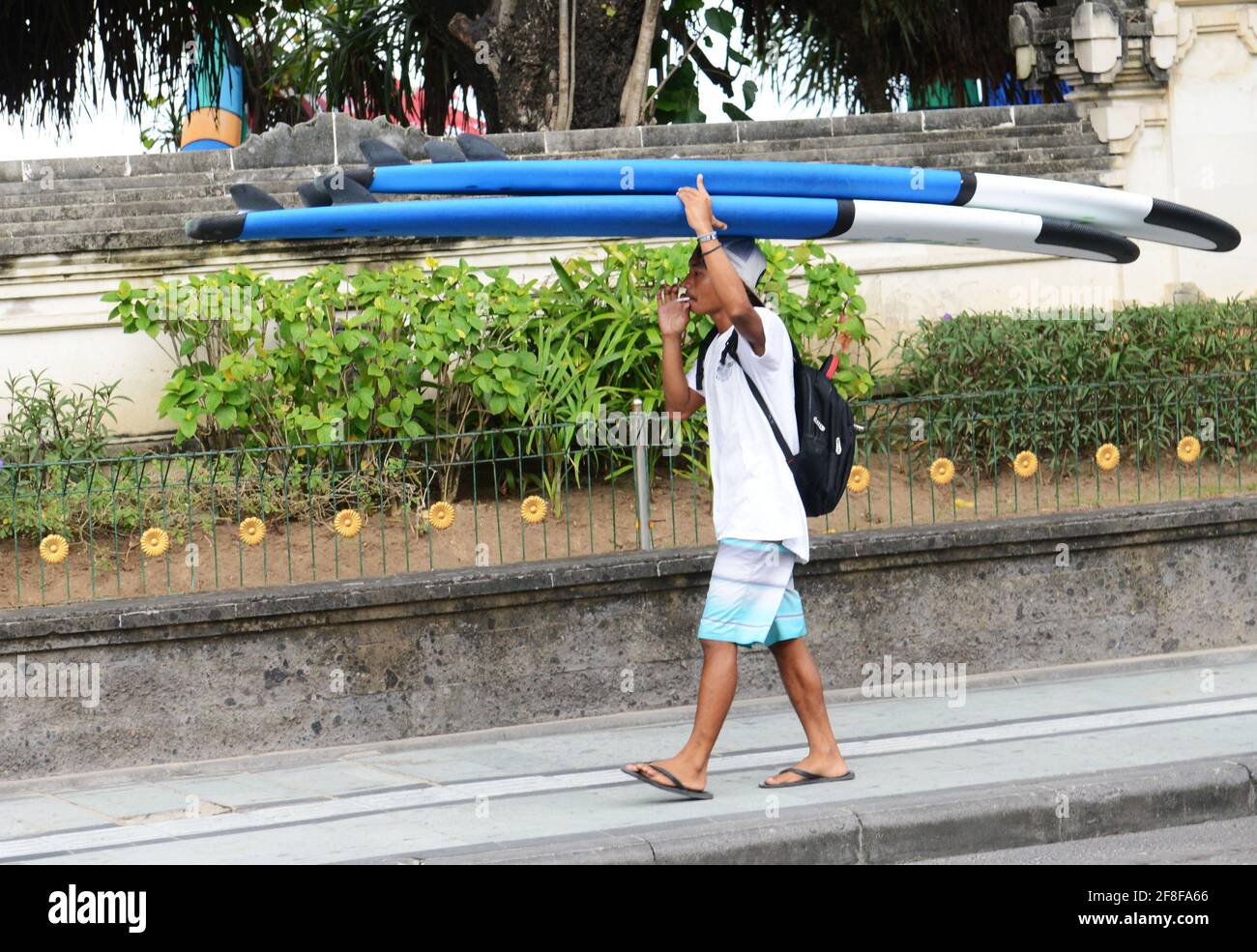 A Balinese man carrying surfing boards on his head Stock Photo - Alamy