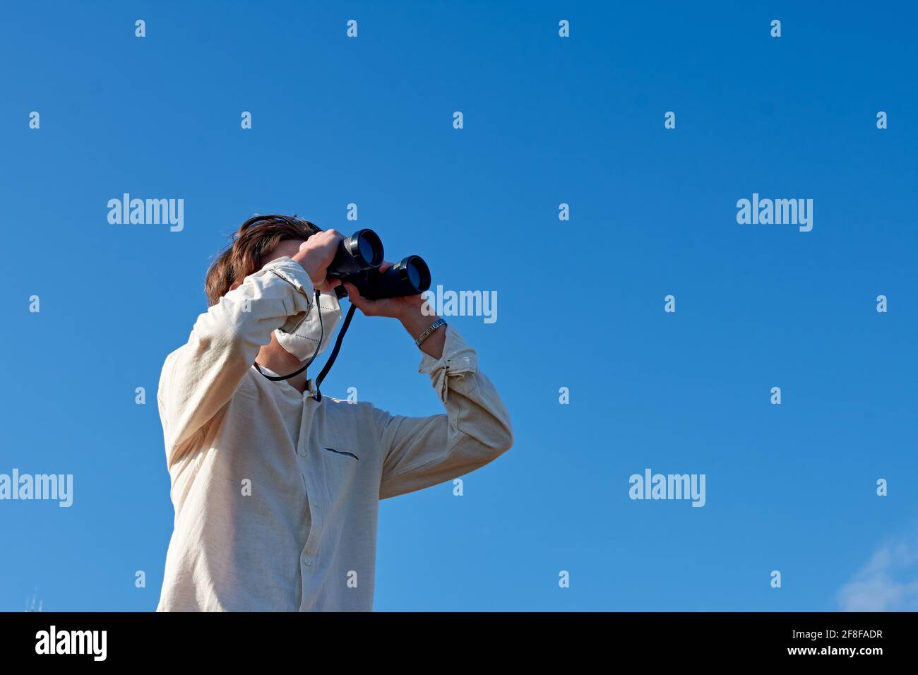 Spanish adventurous male traveler wearing a mask using binoculars and ...