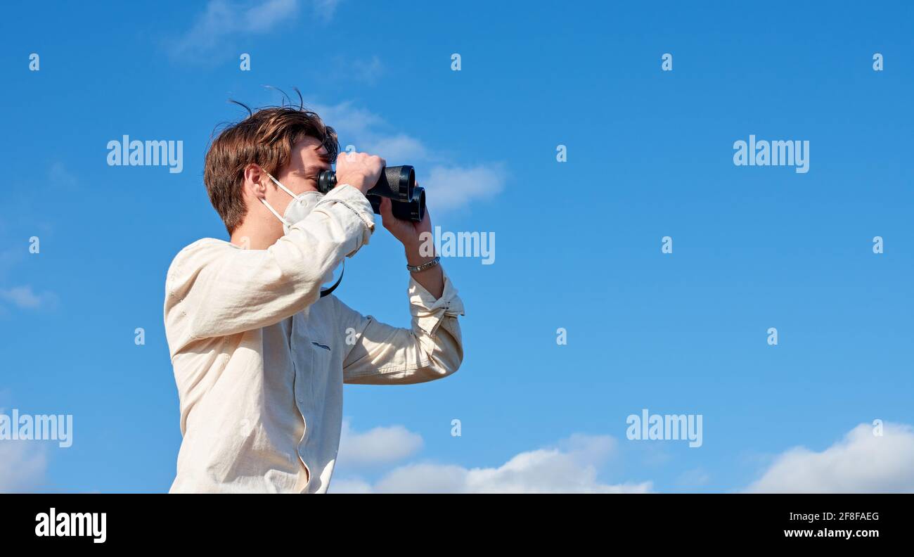 Closeup side view of a young man wearing a white shirt and a face mask ...