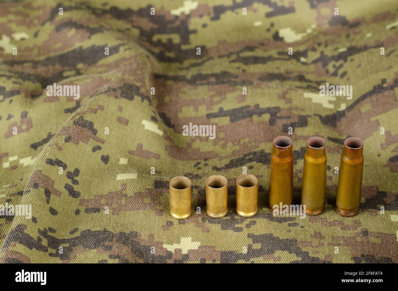 A few random casings on camouflage cloth. A group of pistol and rifle ...