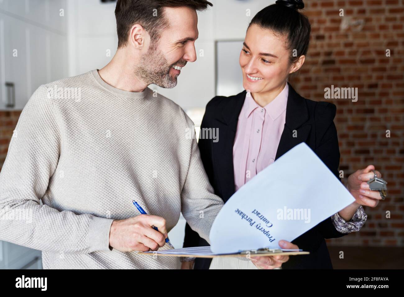 Happy man with estate agent signing contract of new apartment Stock ...