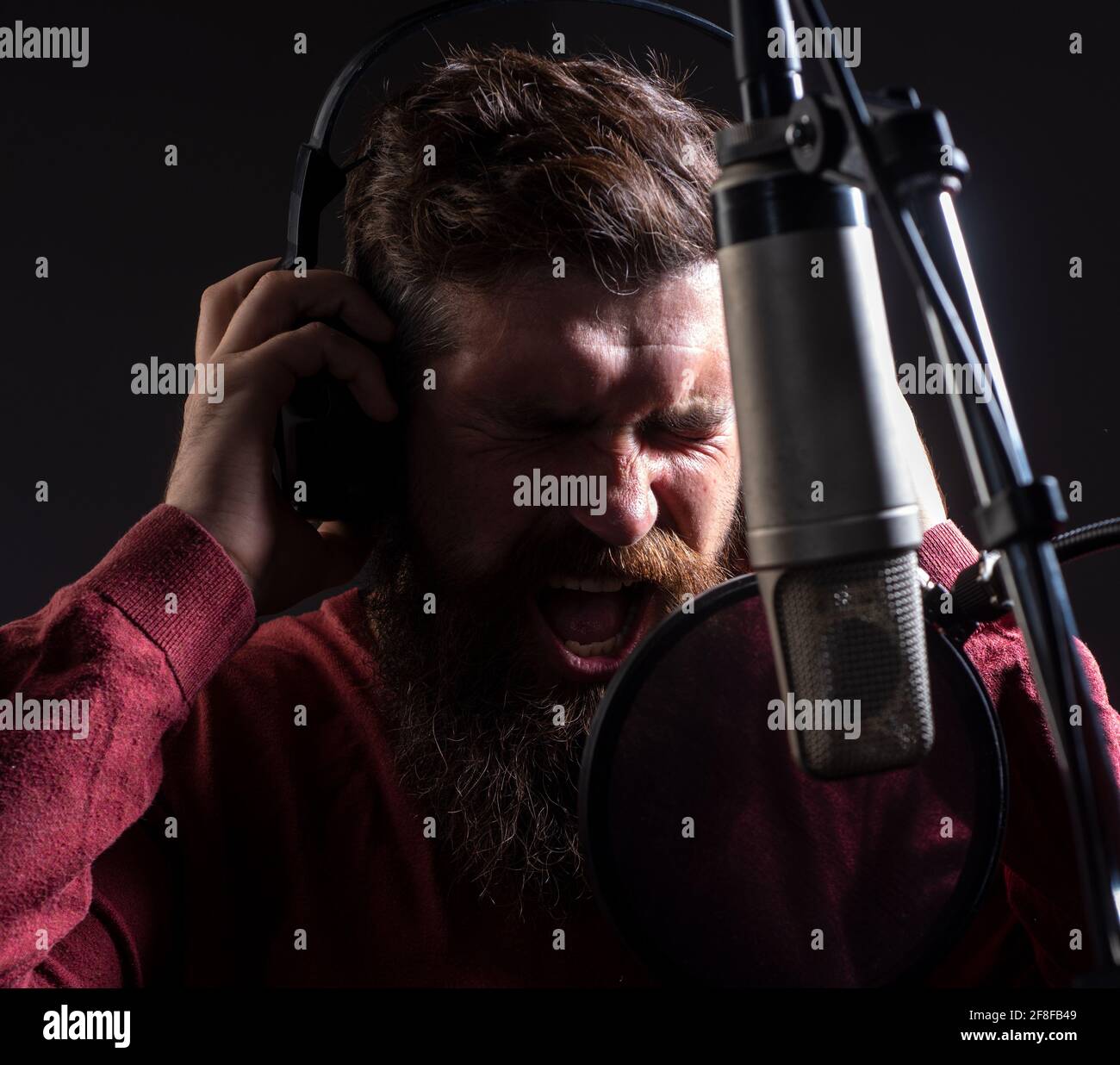 Singer wearing headphones is performing a song with a microphone while ...