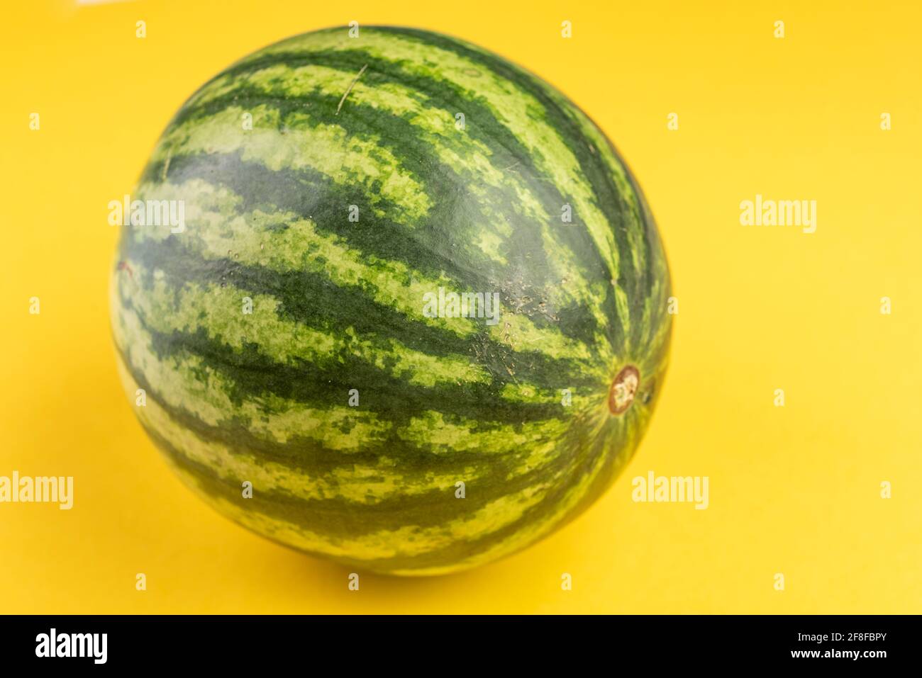 Green watermelon on yellow background side view Stock Photo - Alamy