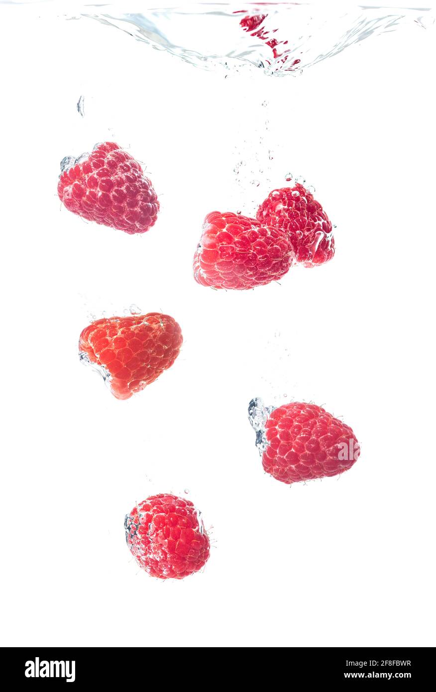 Raspberries splashing in water on white Stock Photo - Alamy