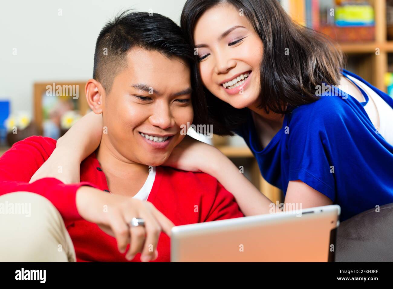 Young Indonesian couple - man and woman - sitting with a tablet ...