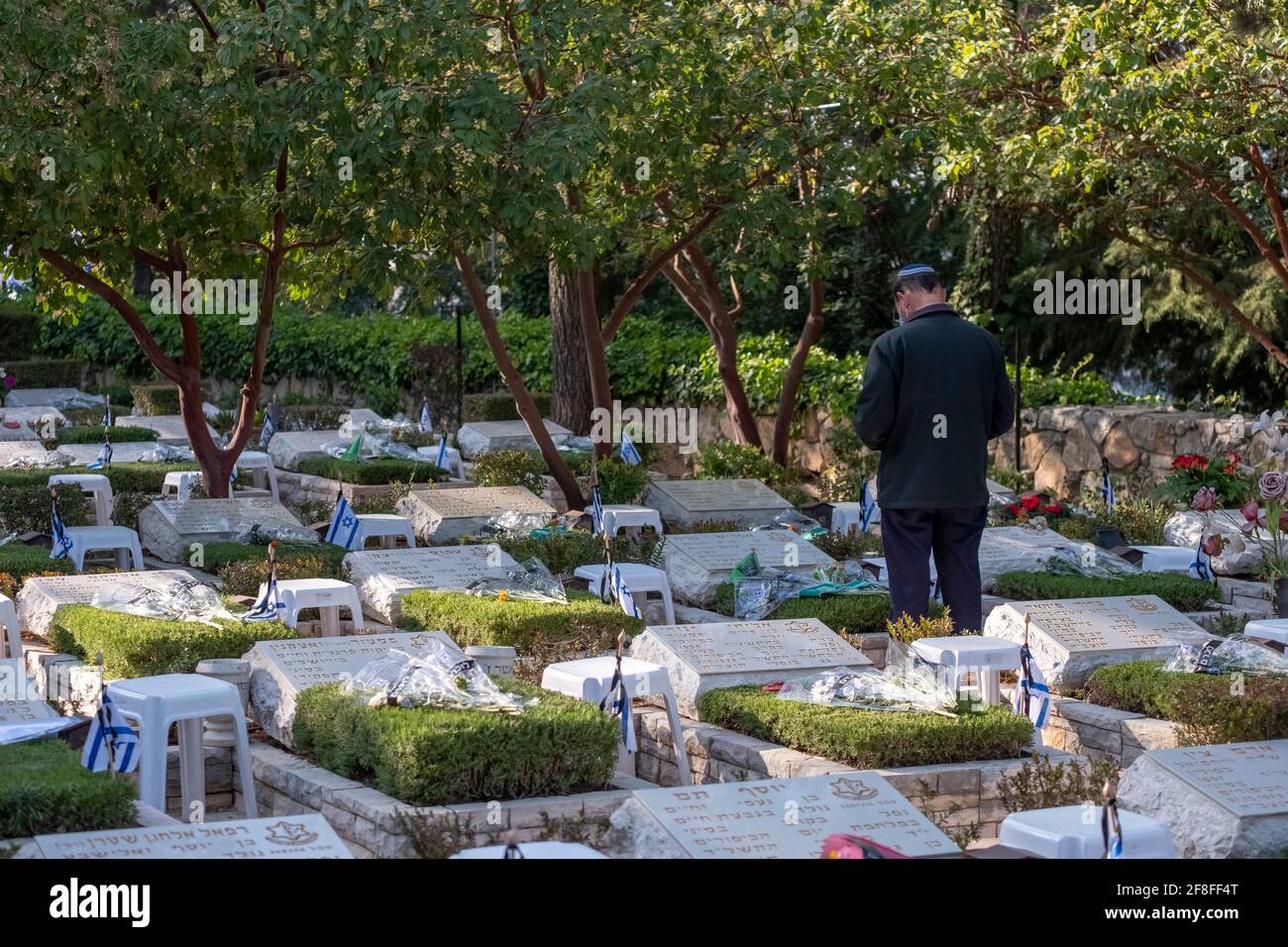 An Israeli man stands by the grave of a loved one as the country ...