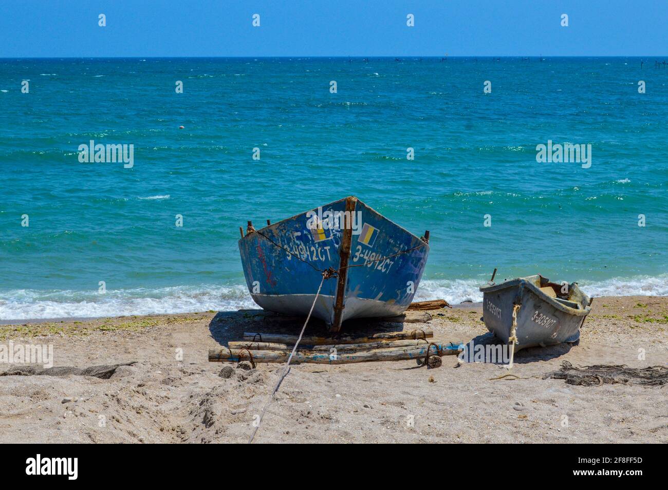 Two old wooden row-boats of different sizes on the sandy beach of the ...