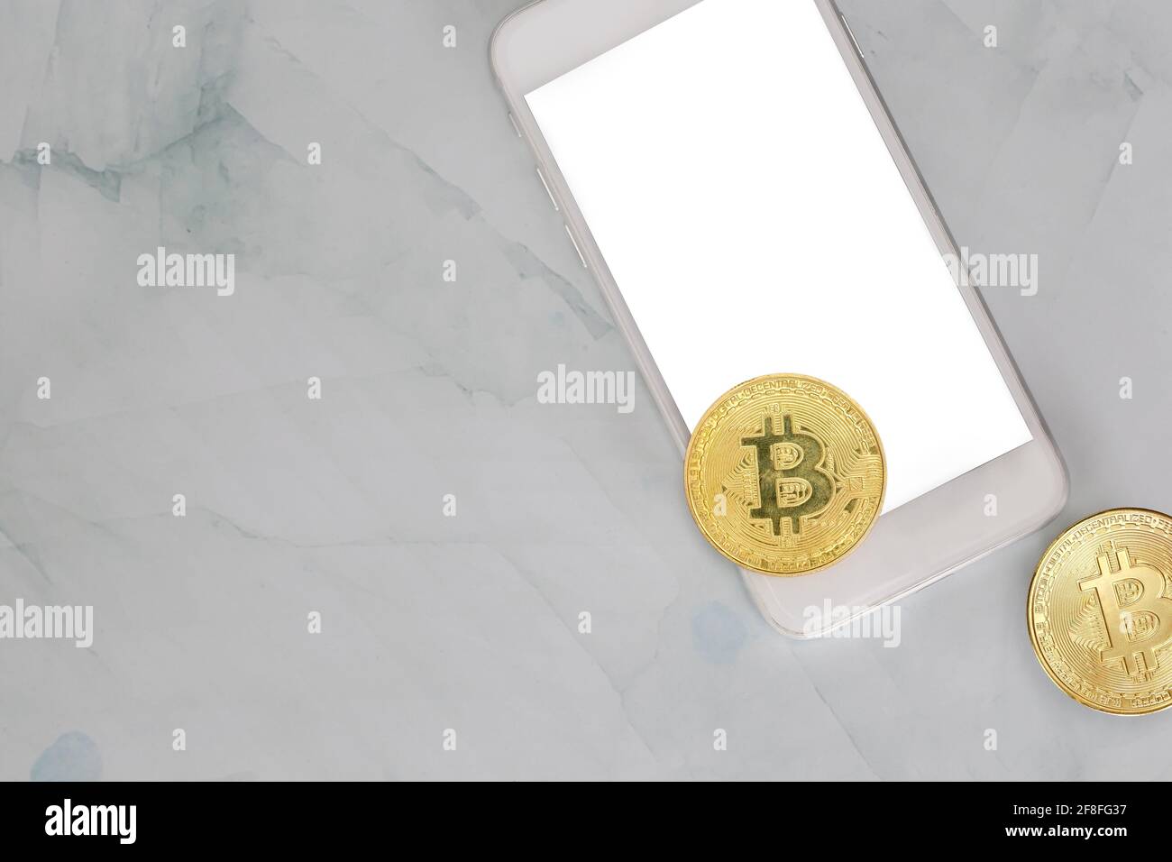 golden bitcoin lies on a smartphone on marble background top view with ...