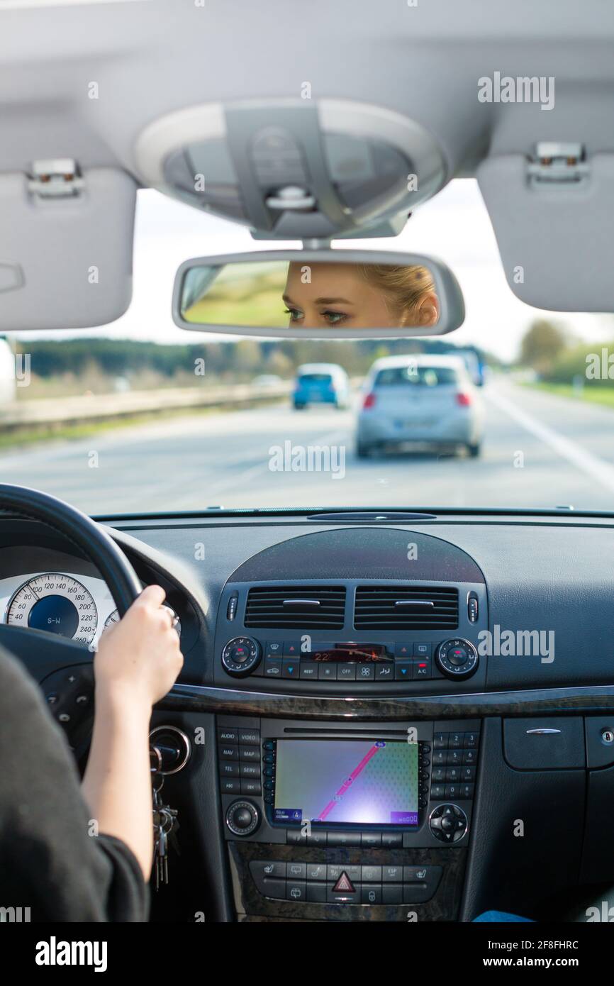 Young woman driving by car on the autobahn, view from inside the auto ...