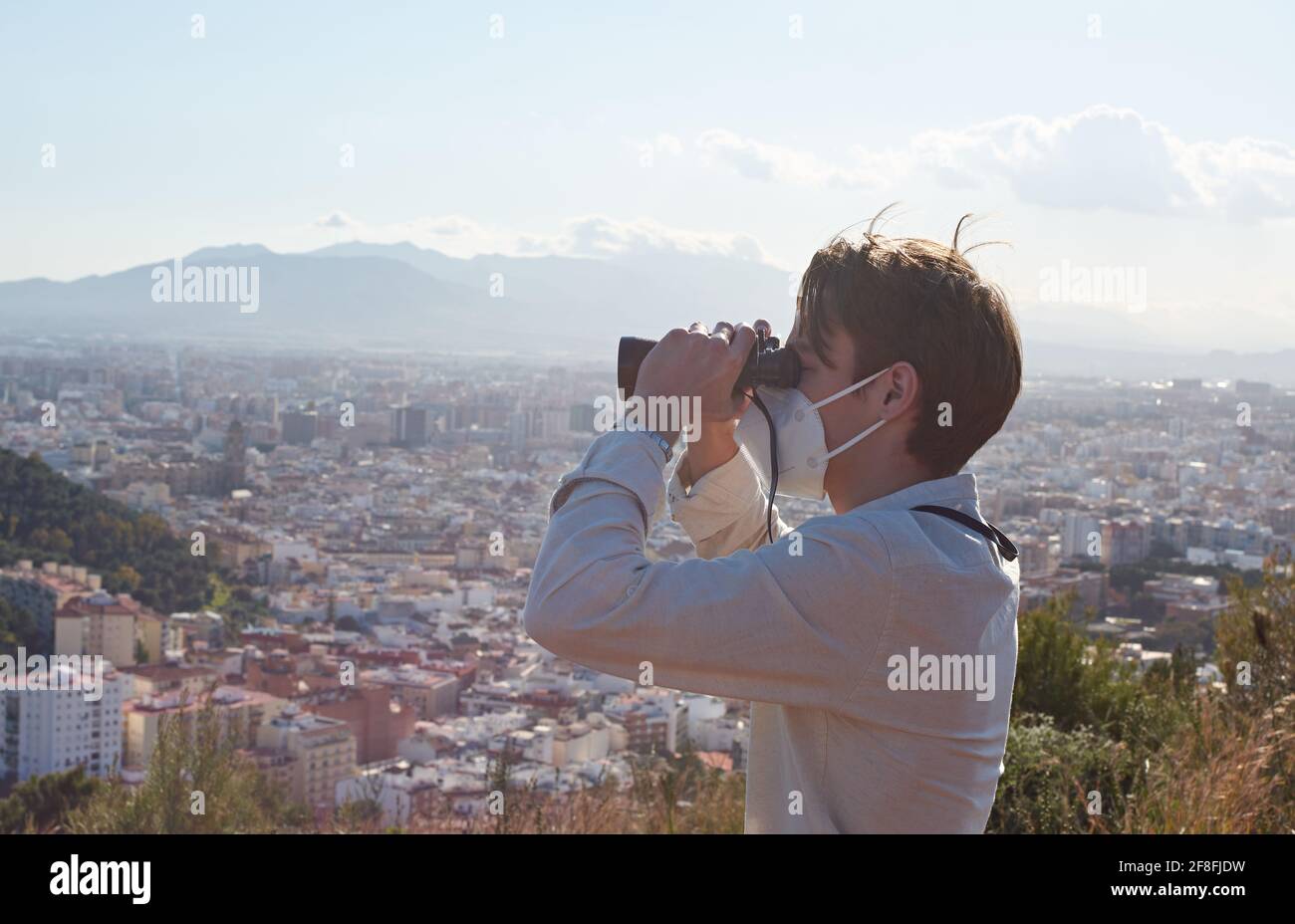 Spanish adventurous male traveler wearing a mask using binoculars and ...