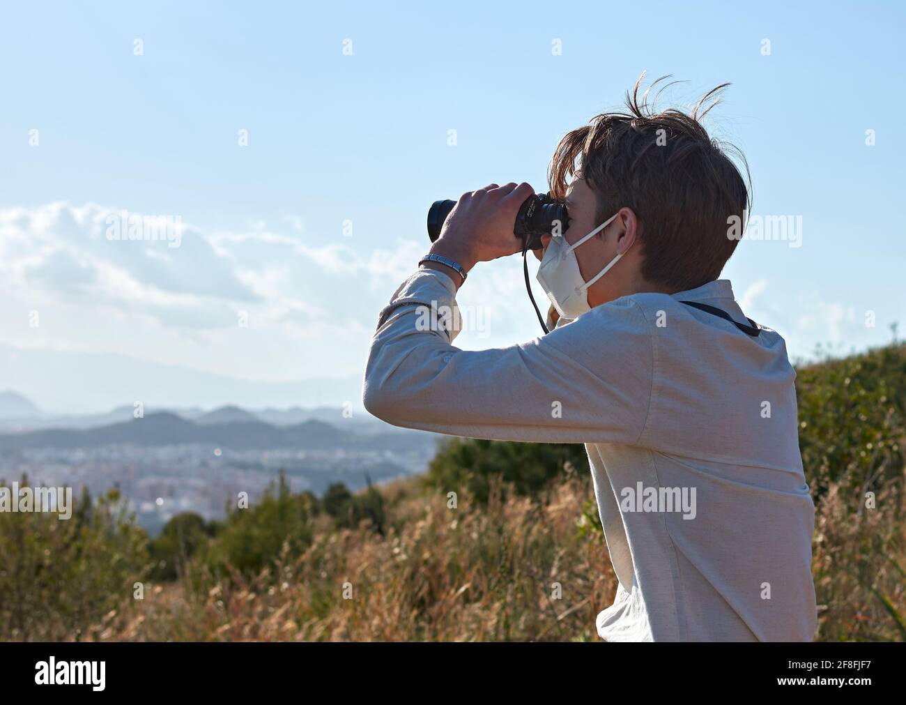 Spanish adventurous male traveler wearing a mask using binoculars and ...