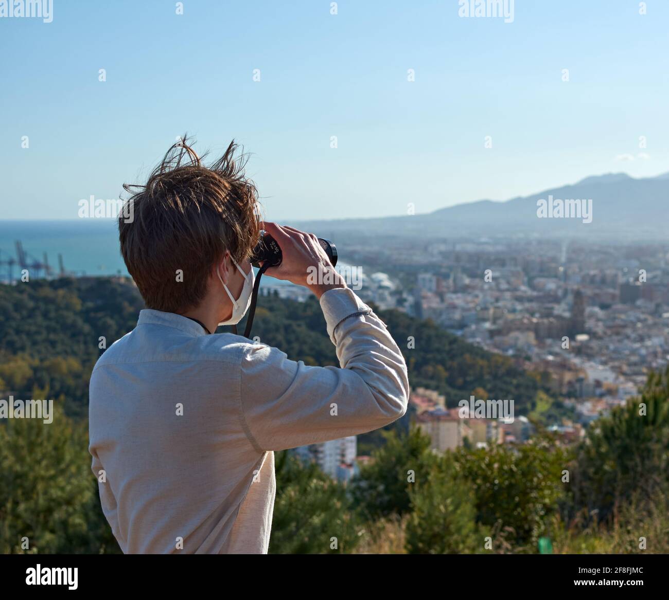 Spanish adventurous male traveler wearing a mask using binoculars and ...