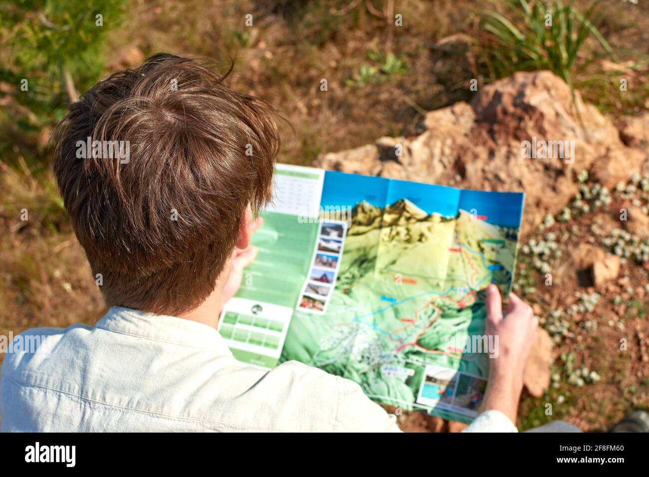 Back view of a young adventurous male traveler holding a map and ...