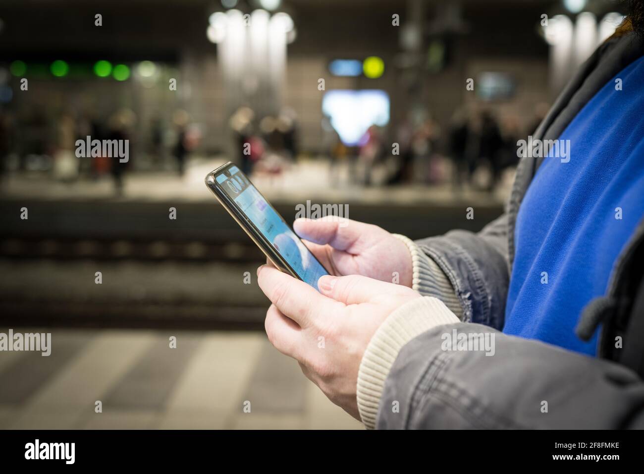 Man on downtown station holding smartphone typing Stock Photo - Alamy