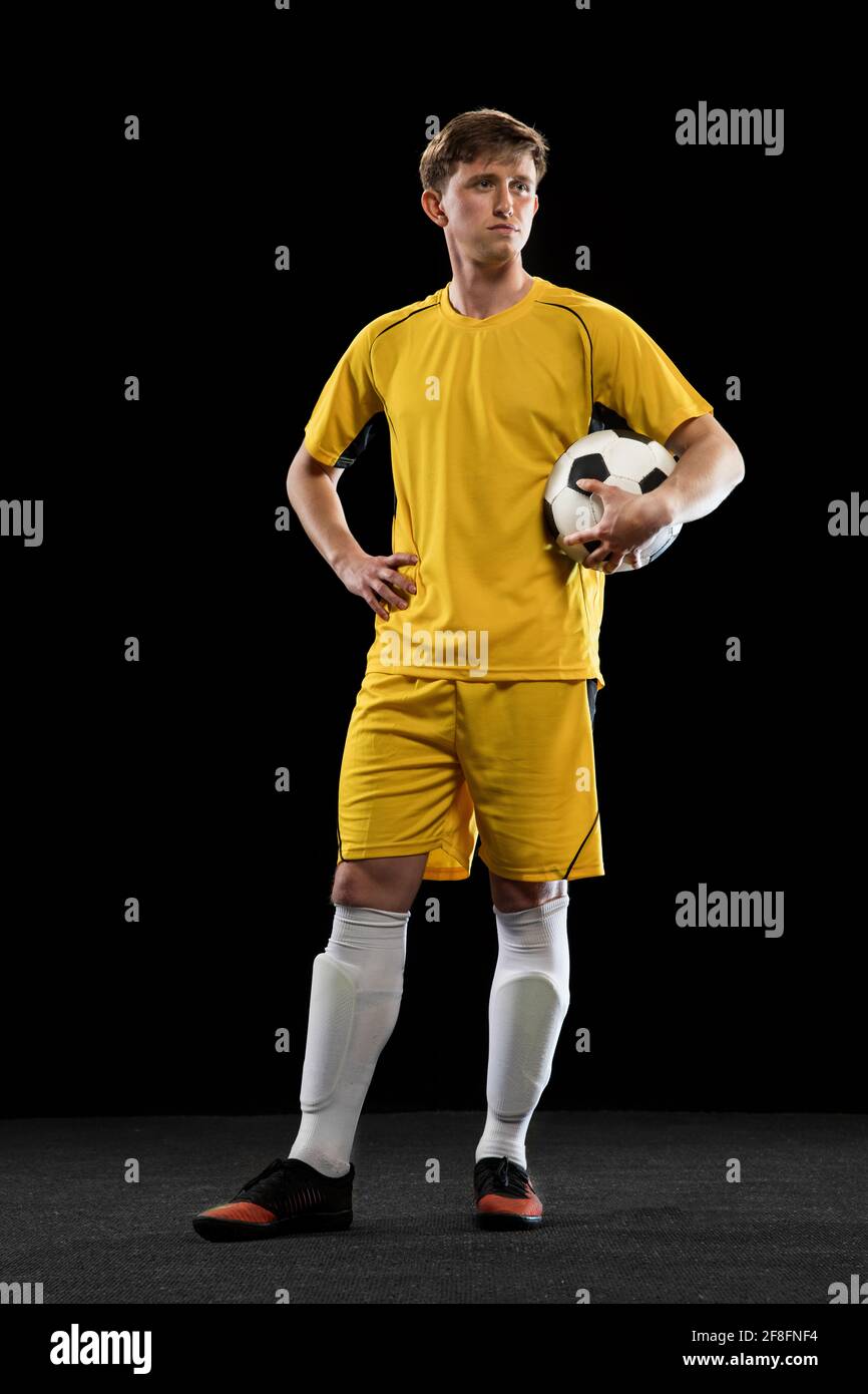 Portrait of young soccer football player posing isolated on black ...