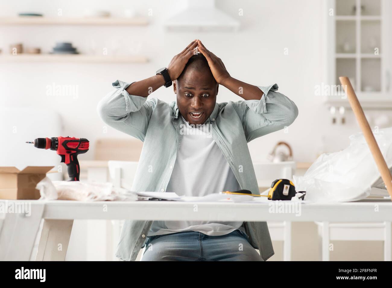 Frightened handyman having problems in assembling new furniture ...