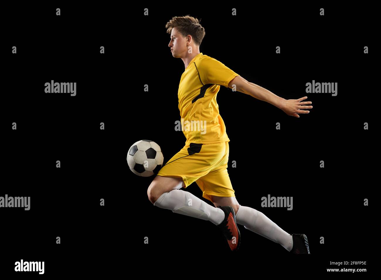 One male soccer player playing football isolated on black background ...