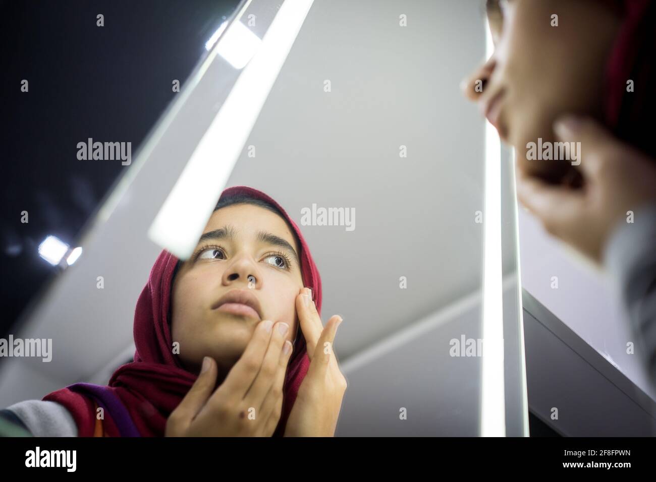 Muslim beautiful girl looking into mirror checking face Stock Photo - Alamy
