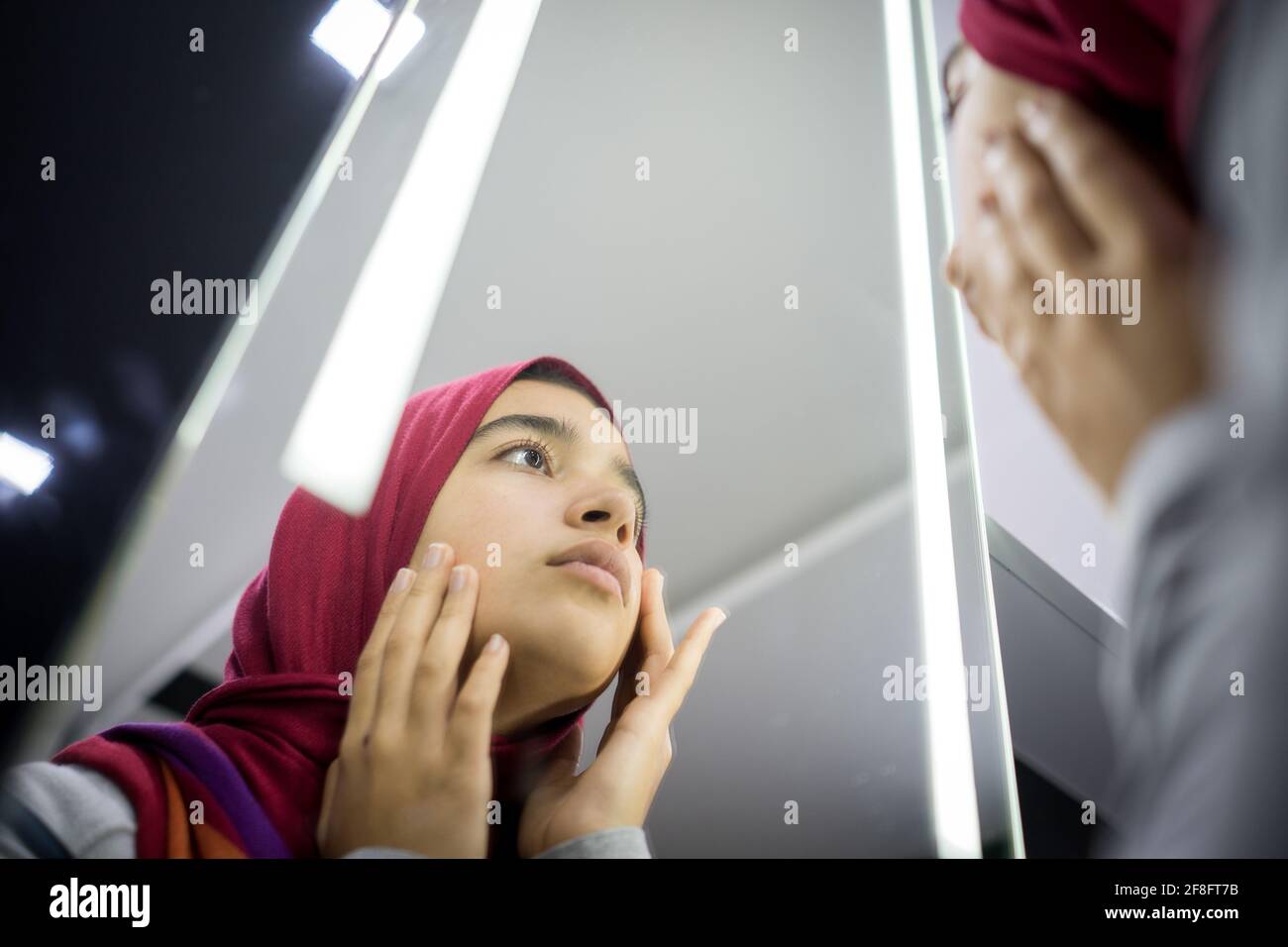 Muslim beautiful girl looking into mirror checking face Stock Photo - Alamy