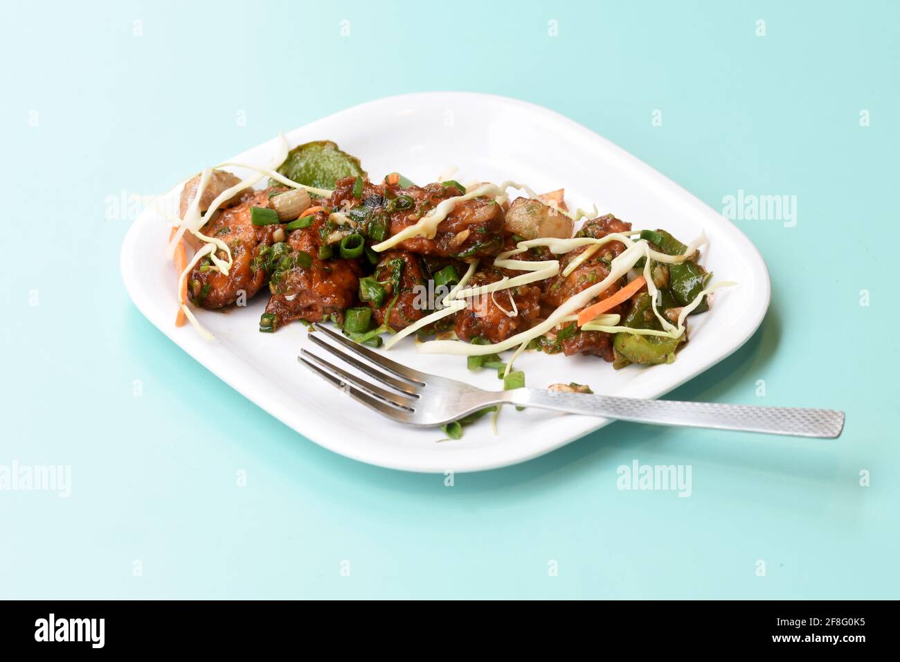 Chilli paneer or Spicy cottage cheese, Garnish with capsicum, onion ...