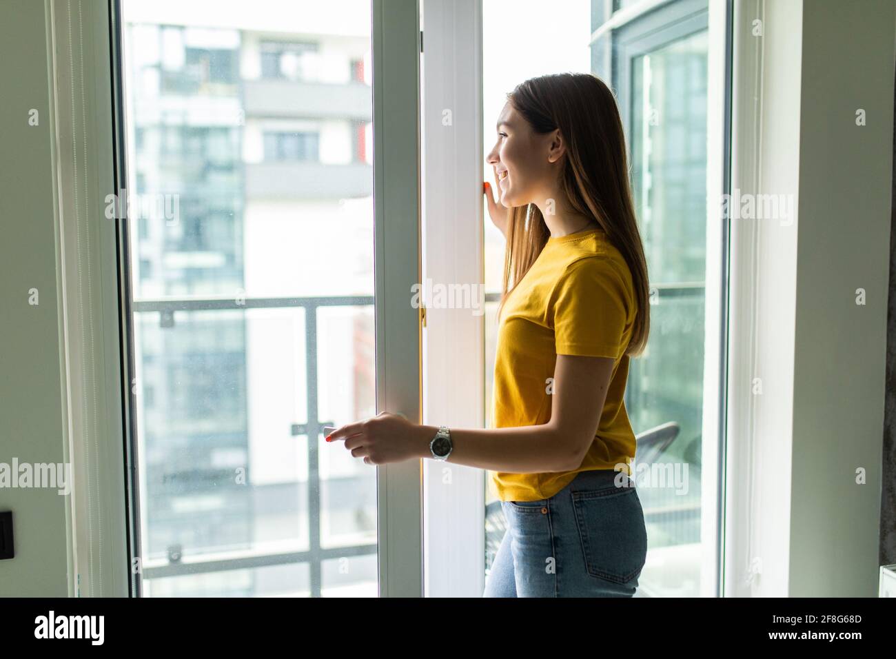 Young woman opening window in living room Stock Photo - Alamy