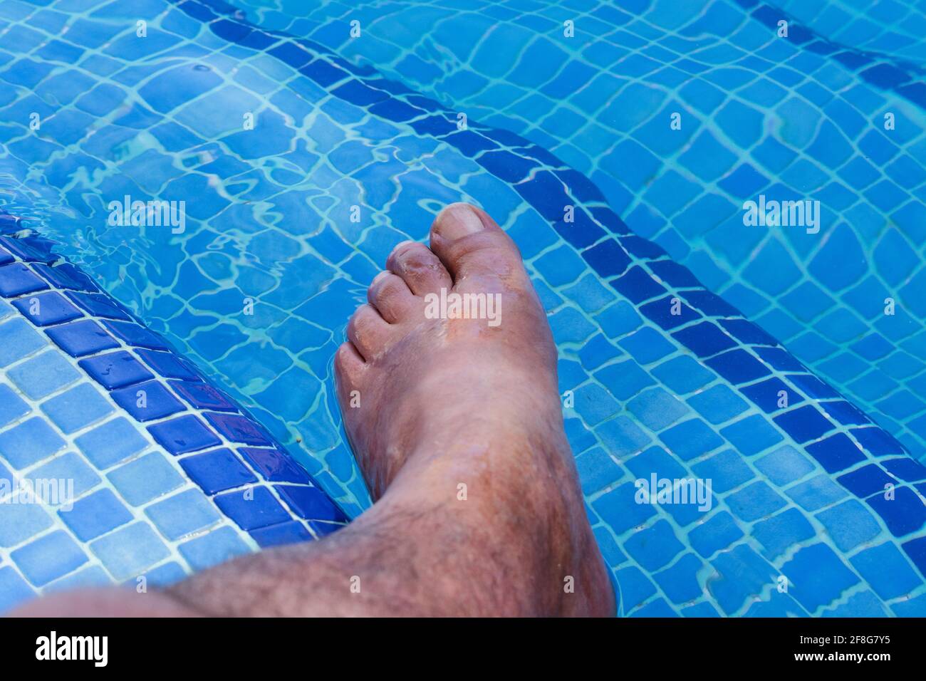 Men feet in a beautiful swimming pool with blue tiles Stock Photo - Alamy