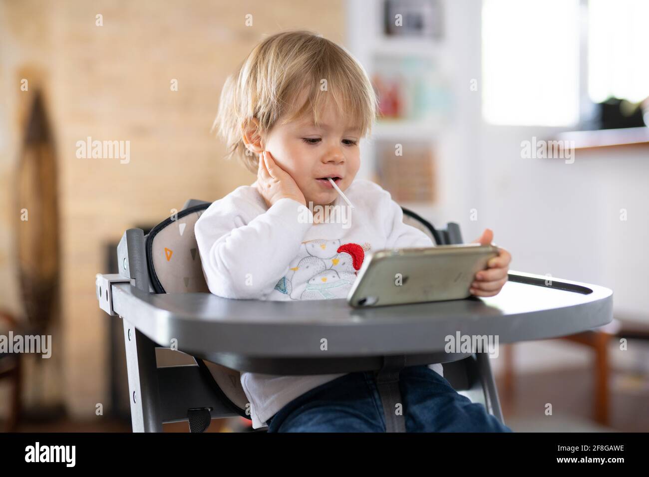 Cute little boy using smartphone, looking at screen, curious child ...