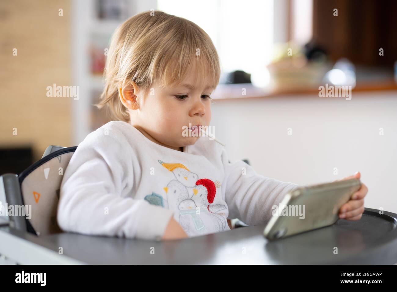 Cute little boy using smartphone, looking at screen, curious child ...