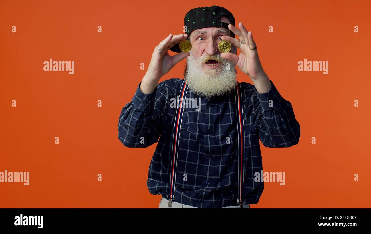 Mature old bearded stylish man showing golden bitcoins, cryptocurrency ...