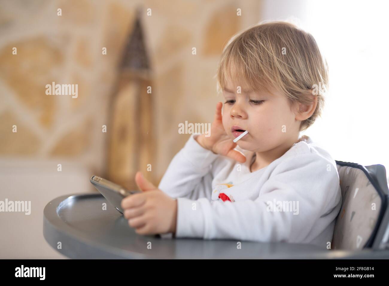 Cute little boy using smartphone, looking at screen, curious child ...