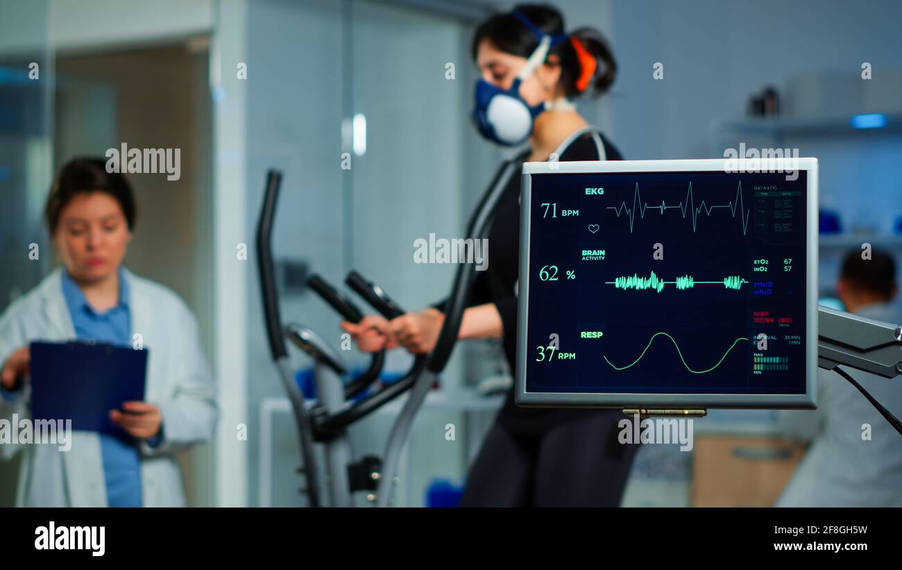 Monitor showing EKG scan of athlete running on cross trainer and ...
